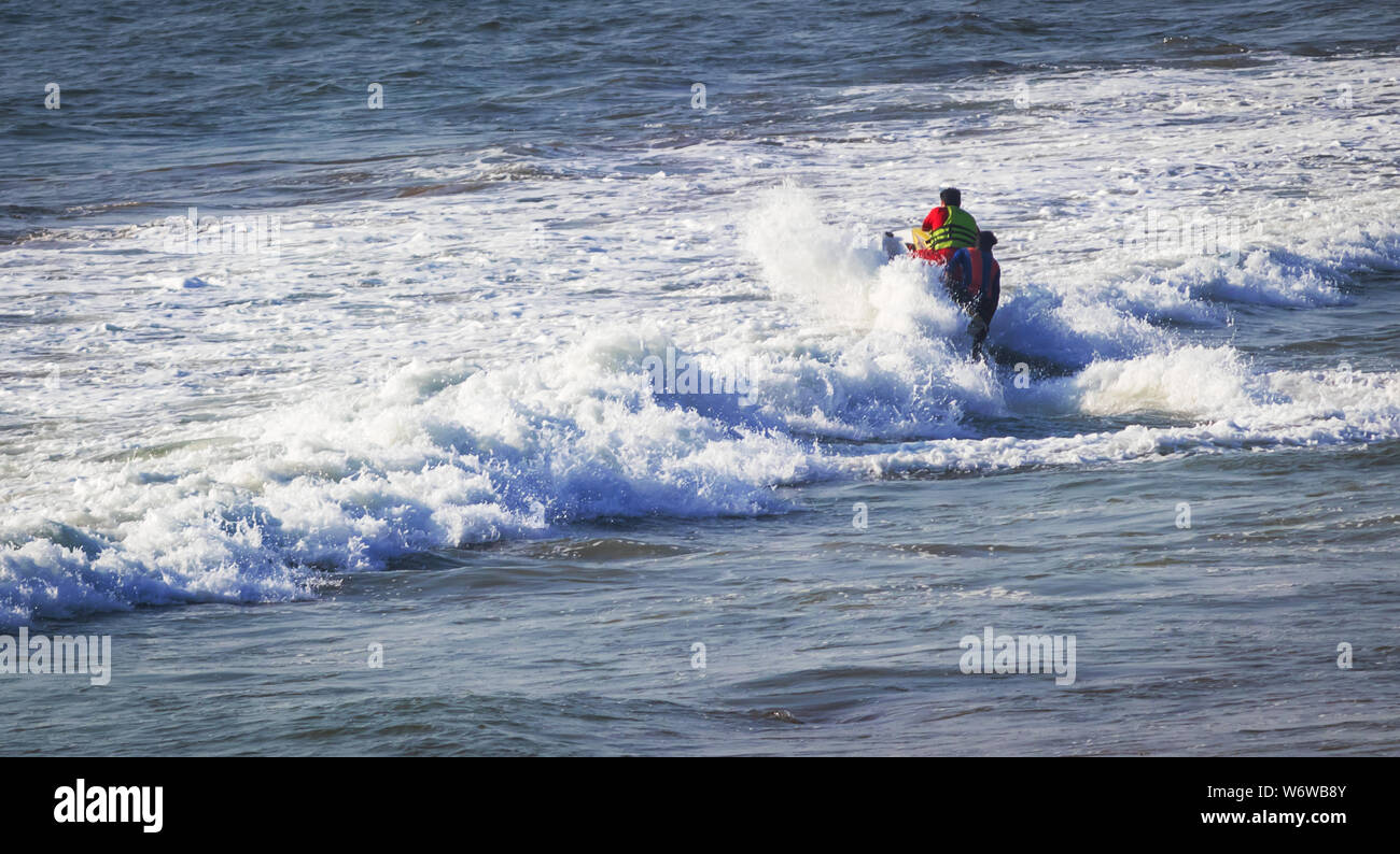 Young couple riding a jet ski / wave runner in Goa sea, wearing safety ...