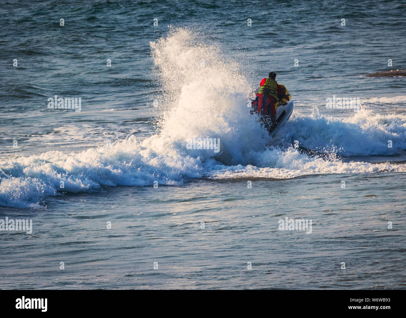 Young couple riding a jet ski / wave runner in Goa sea, wearing safety ...