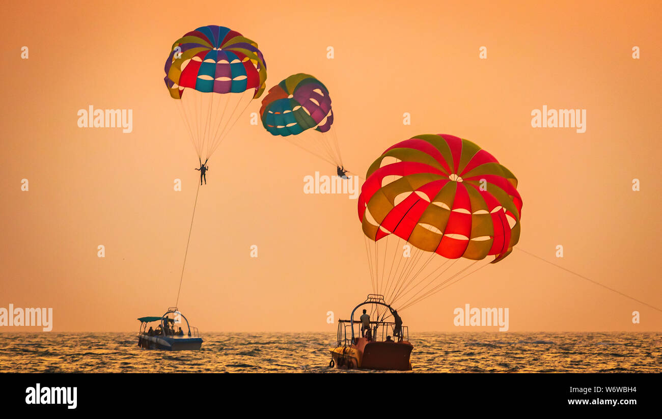 amazing shot at sunset of Parasailing water amusement - flying on a ...