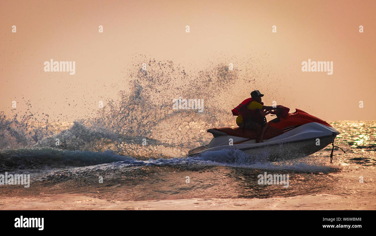 Young couple riding a jet ski / wave runner in Goa sea, wearing safety ...