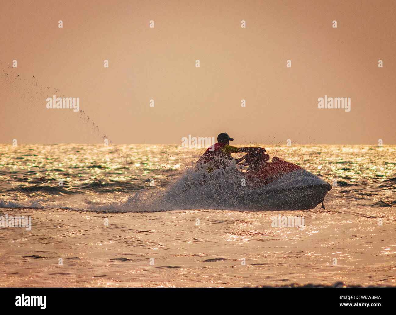Young couple riding a jet ski / wave runner in Goa sea, wearing safety ...