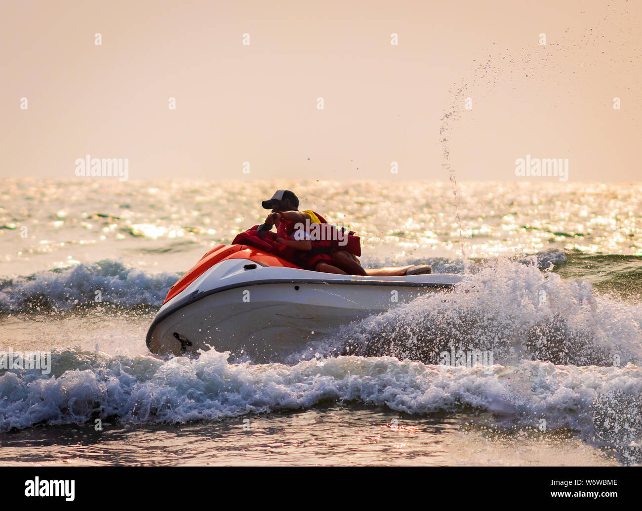 Young couple riding a jet ski / wave runner in Goa sea, wearing safety ...