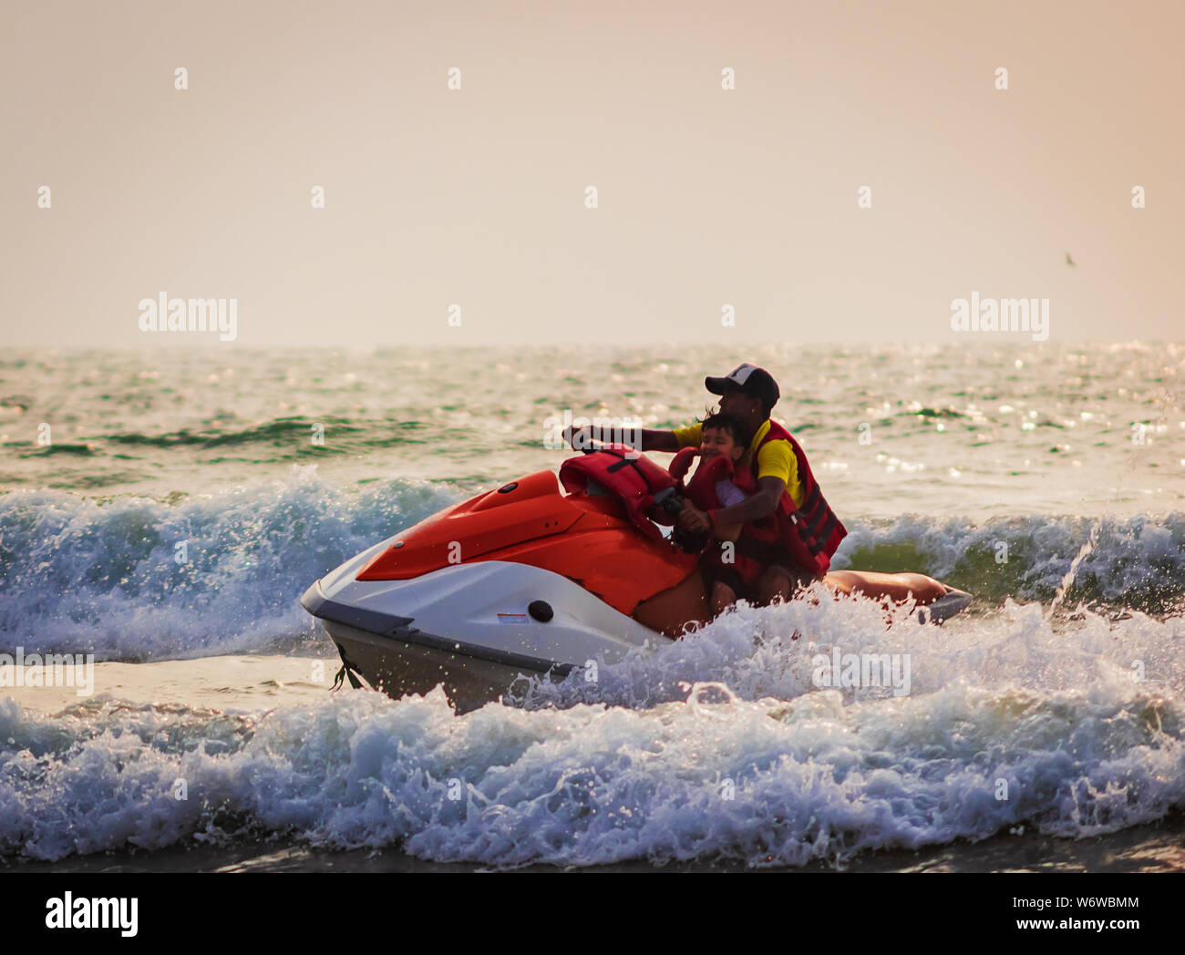 Young couple riding a jet ski / wave runner in Goa sea, wearing safety ...