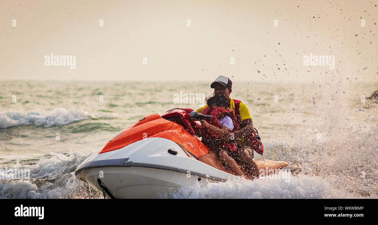 Young couple riding a jet ski / wave runner in Goa sea, wearing safety ...