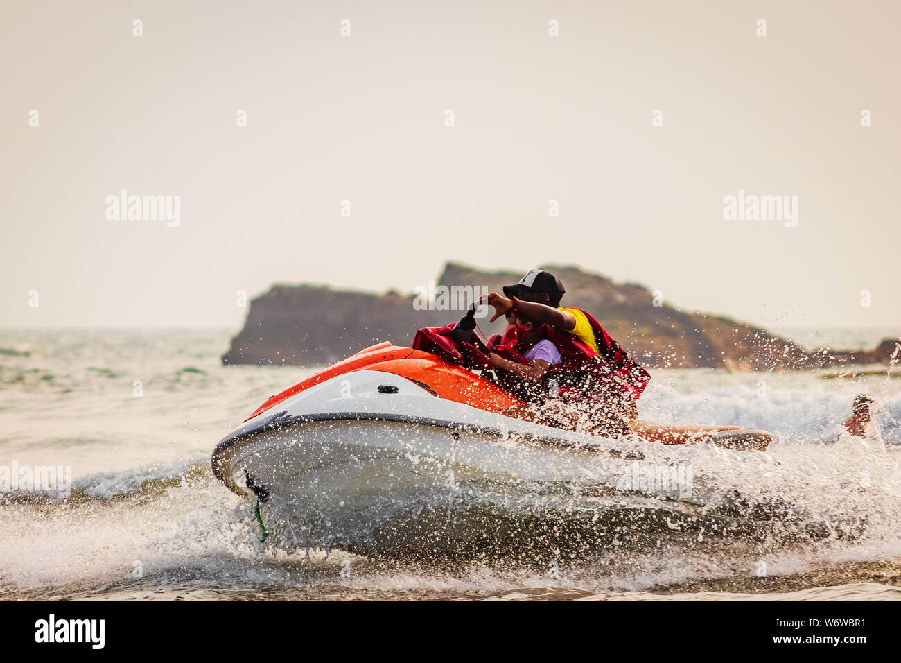 Young couple riding a jet ski / wave runner in Goa sea, wearing safety ...