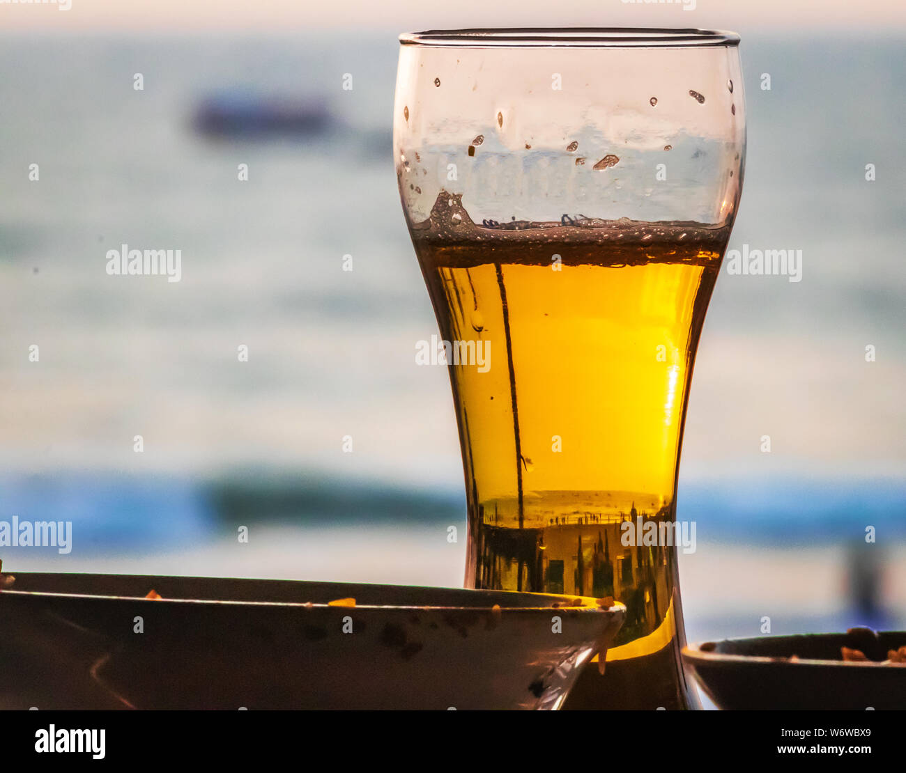 Cold beer on desk and background of summer beach with palm vagator ...