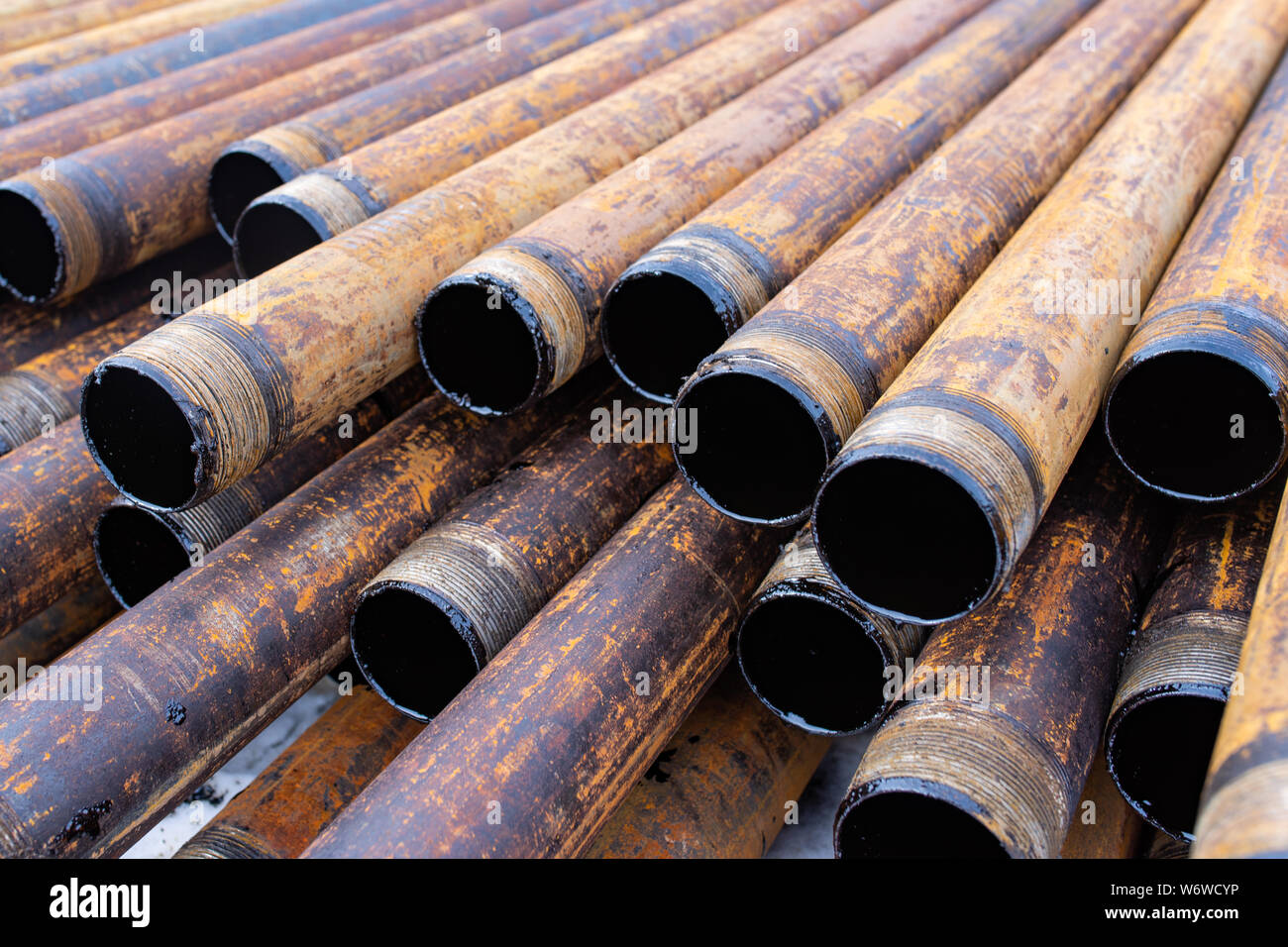 Salvaged pipes and casings are lined up on racks in storage on a ...