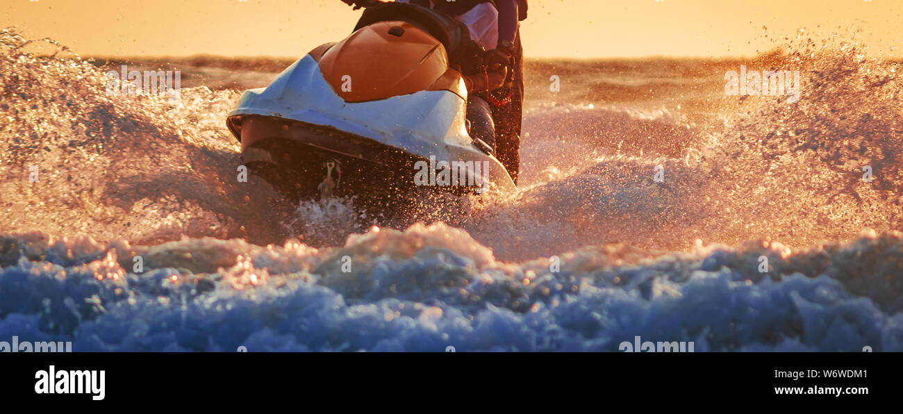Young couple riding a jet ski / wave runner in Goa sea, wearing safety ...