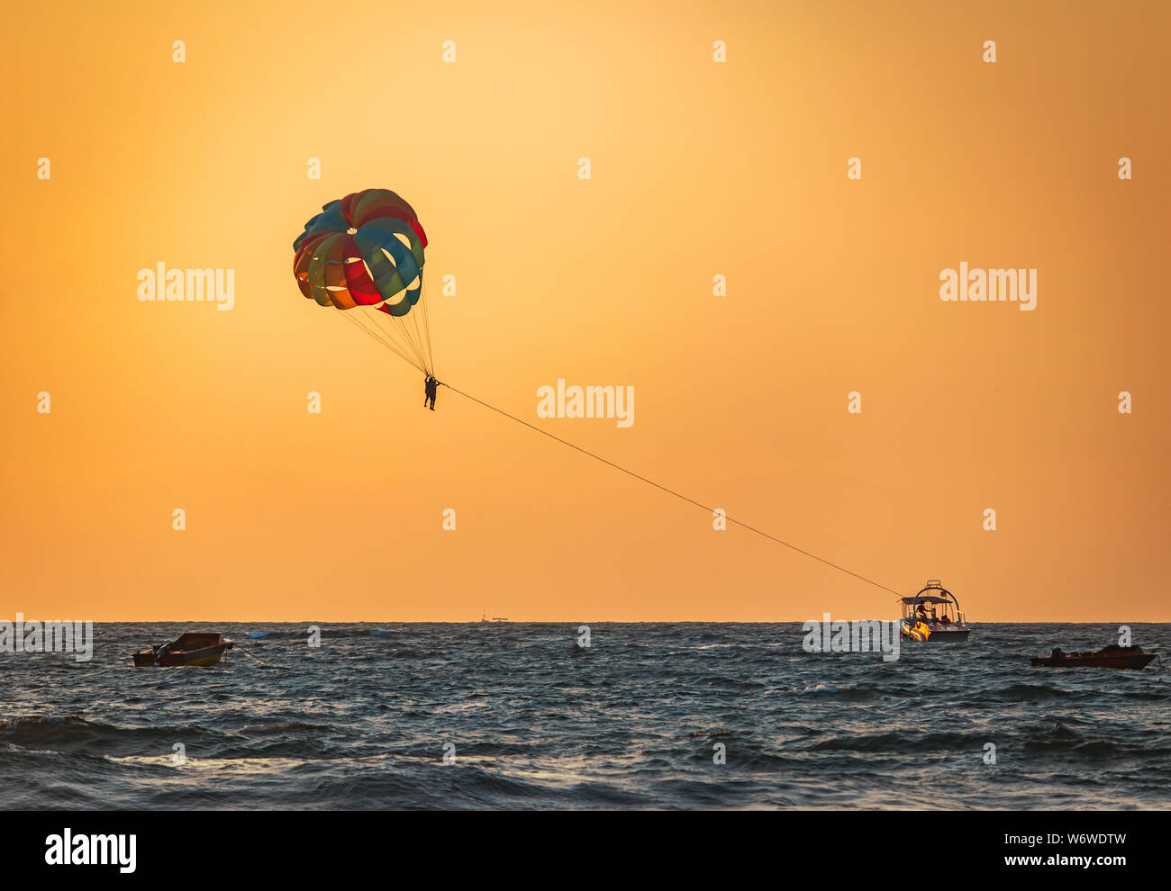 amazing shot at sunset of Parasailing water amusement - flying on a ...