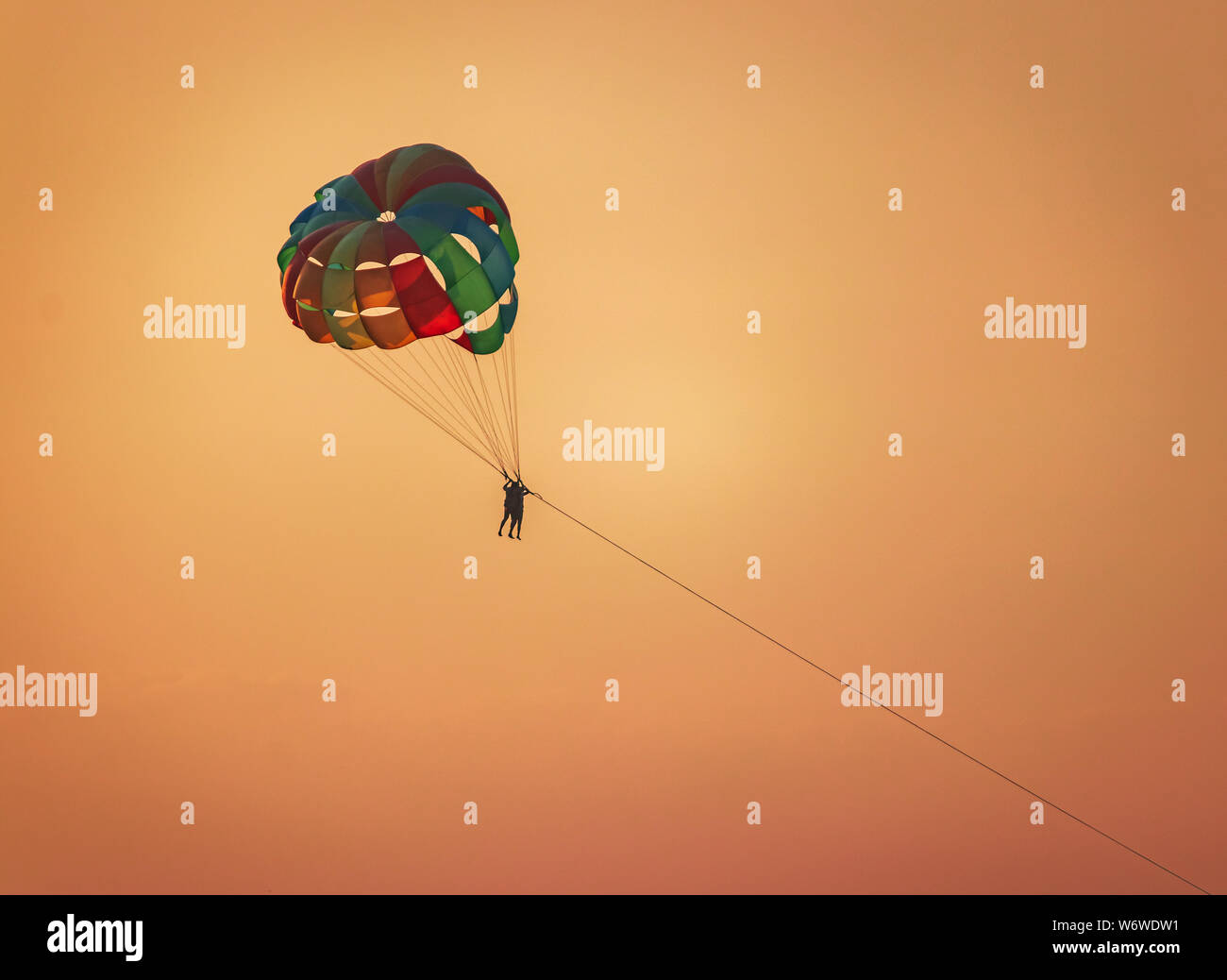 amazing shot at sunset of Parasailing water amusement - flying on a ...