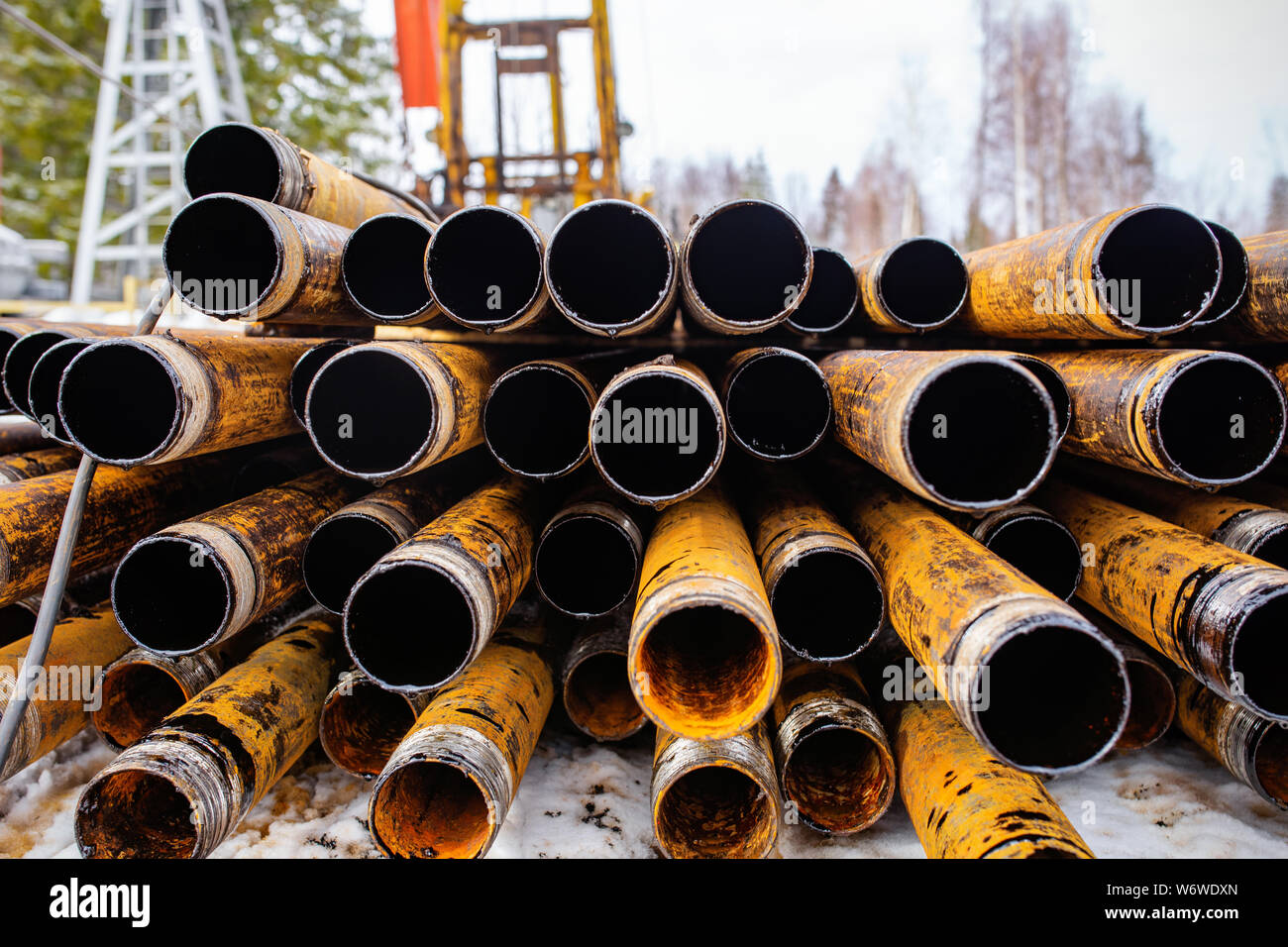 Salvaged pipes and casings are lined up on racks in storage on a ...