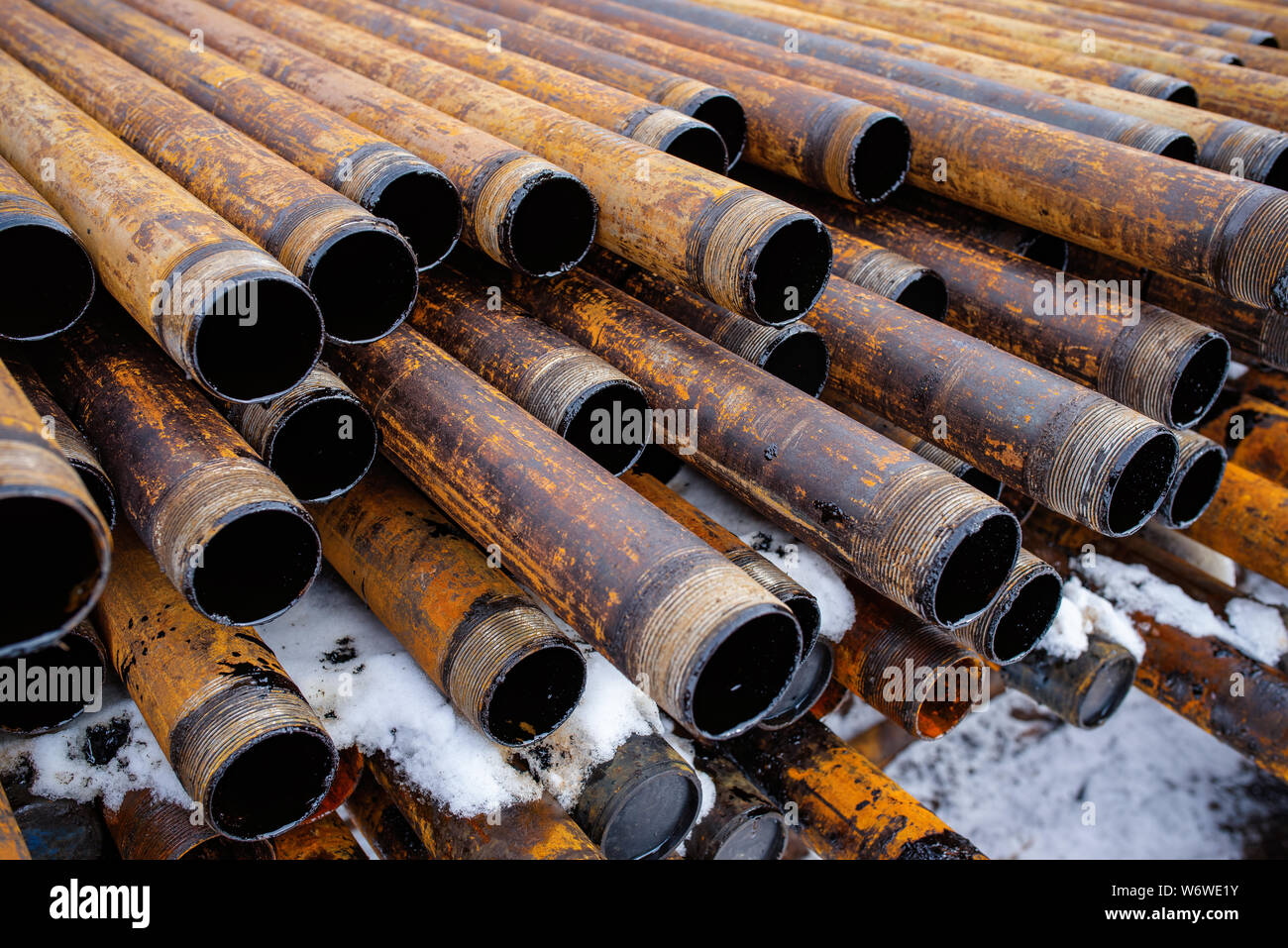 Salvaged pipes and casings are lined up on racks in storage on a ...
