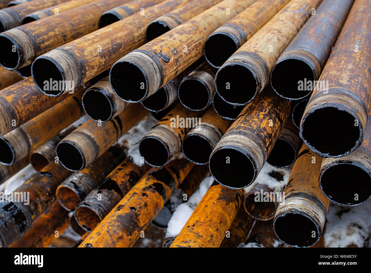 Salvaged pipes and casings are lined up on racks in storage on a ...