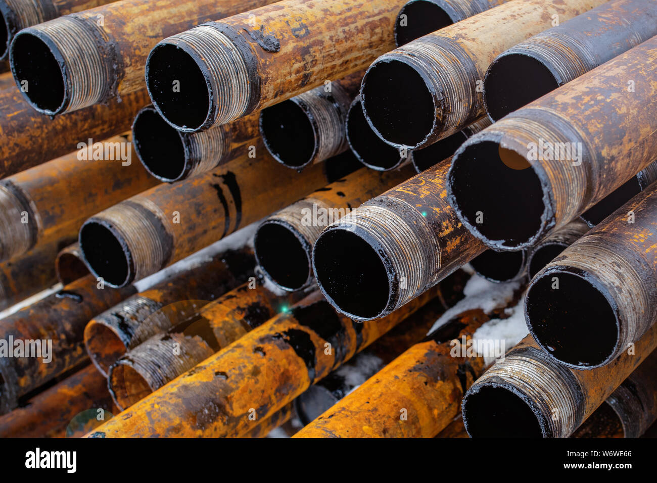 Salvaged pipes and casings are lined up on racks in storage on a ...