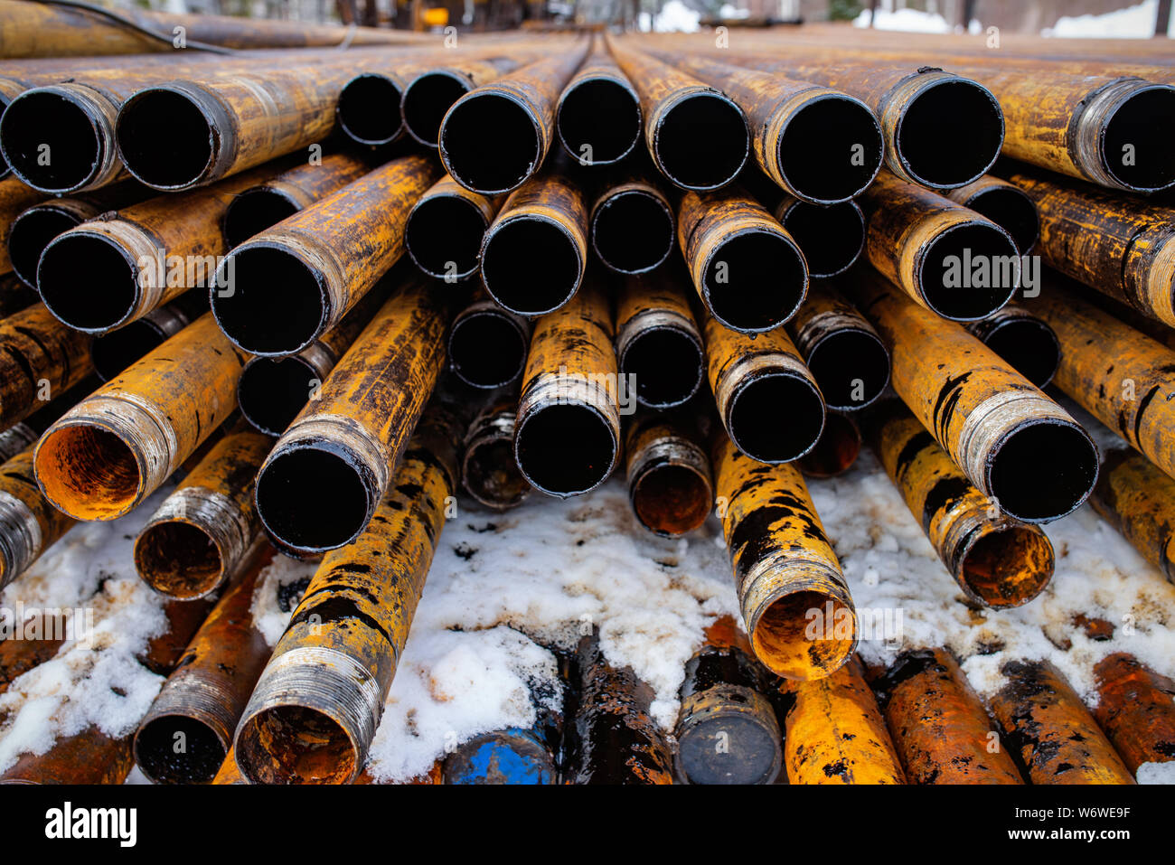 Salvaged pipes and casings are lined up on racks in storage on a ...
