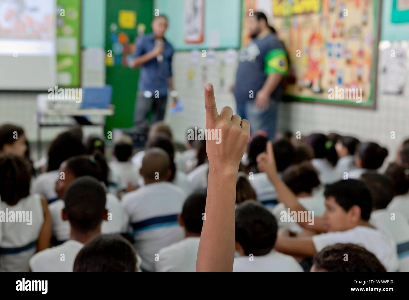 Brazilian classroom with a boys arm showing a forefinger to ask a ...