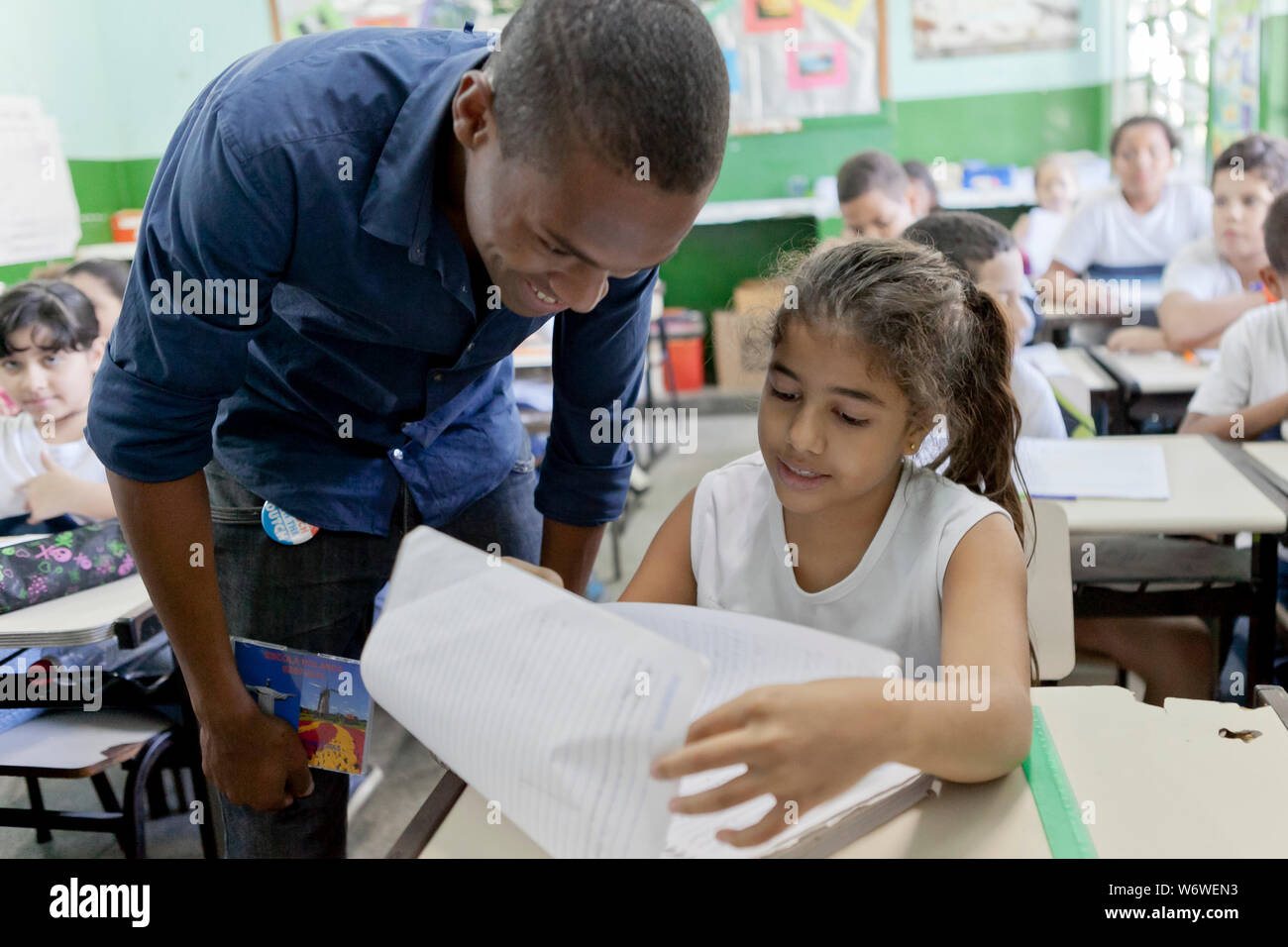 Young Brazilian school girl in classroom showing a teacher her ...