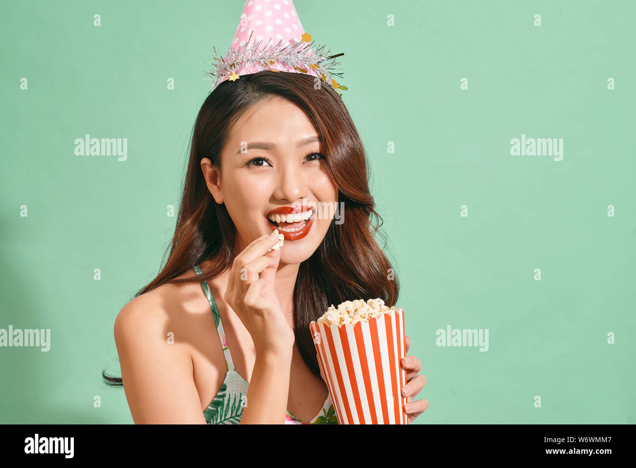 Happy woman eating popcorn on blue background Stock Photo - Alamy
