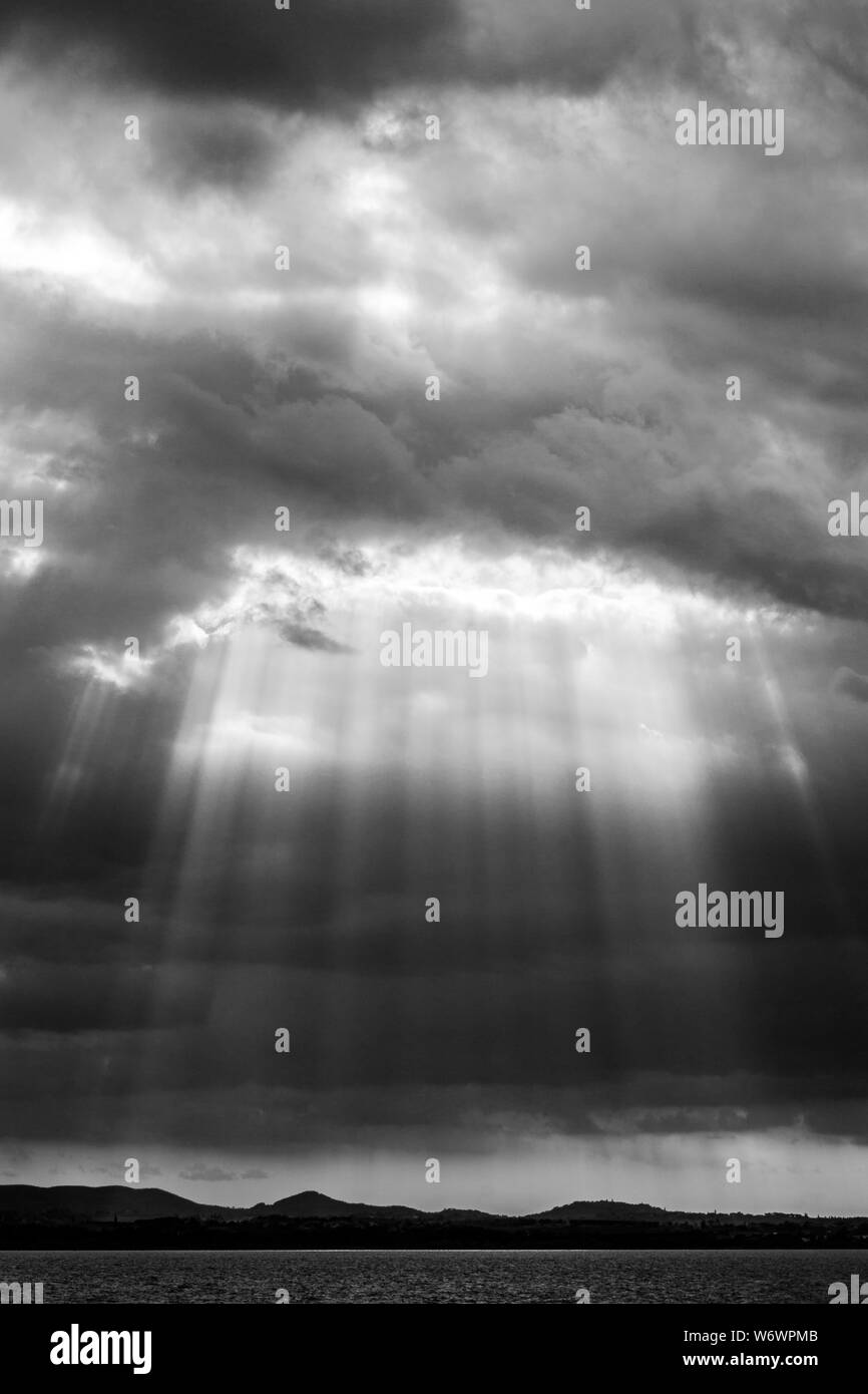Sunrays with dark clouds in the background and Trasimeno lake (Umbria ...