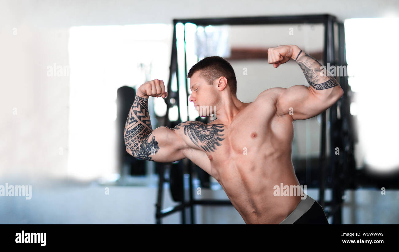male bodybuilder performs exercises in front of a mirror . photo with ...