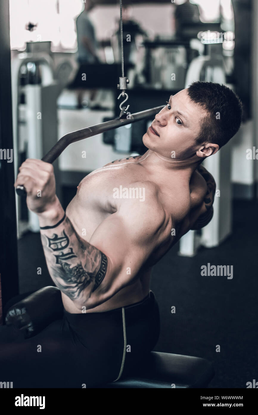 close up. male bodybuilder uses the simulator to strengthen the muscles ...