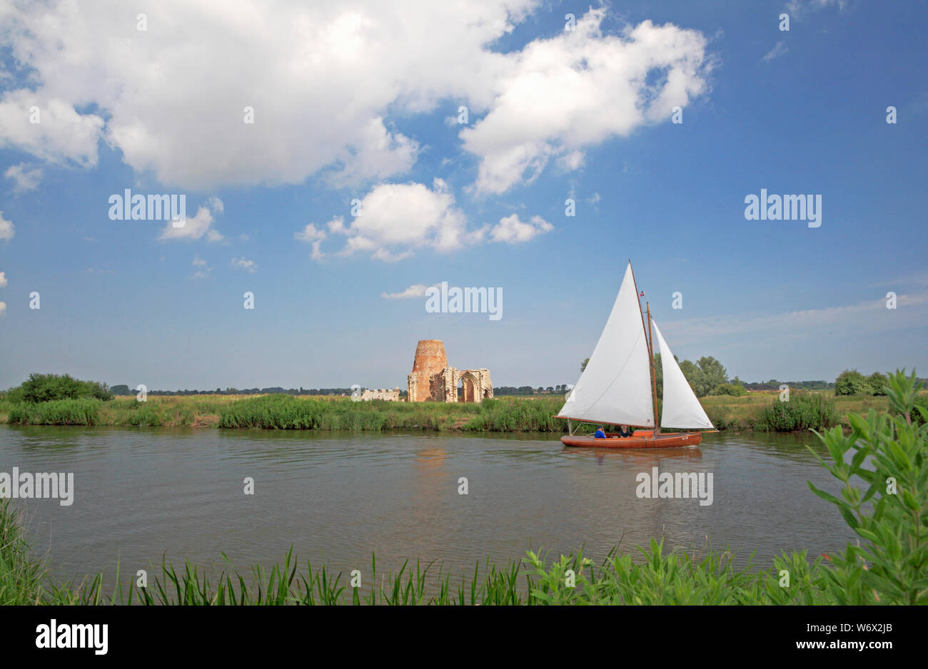 A yacht in full sail on the River Bure on the Norfolk Broads passing St ...