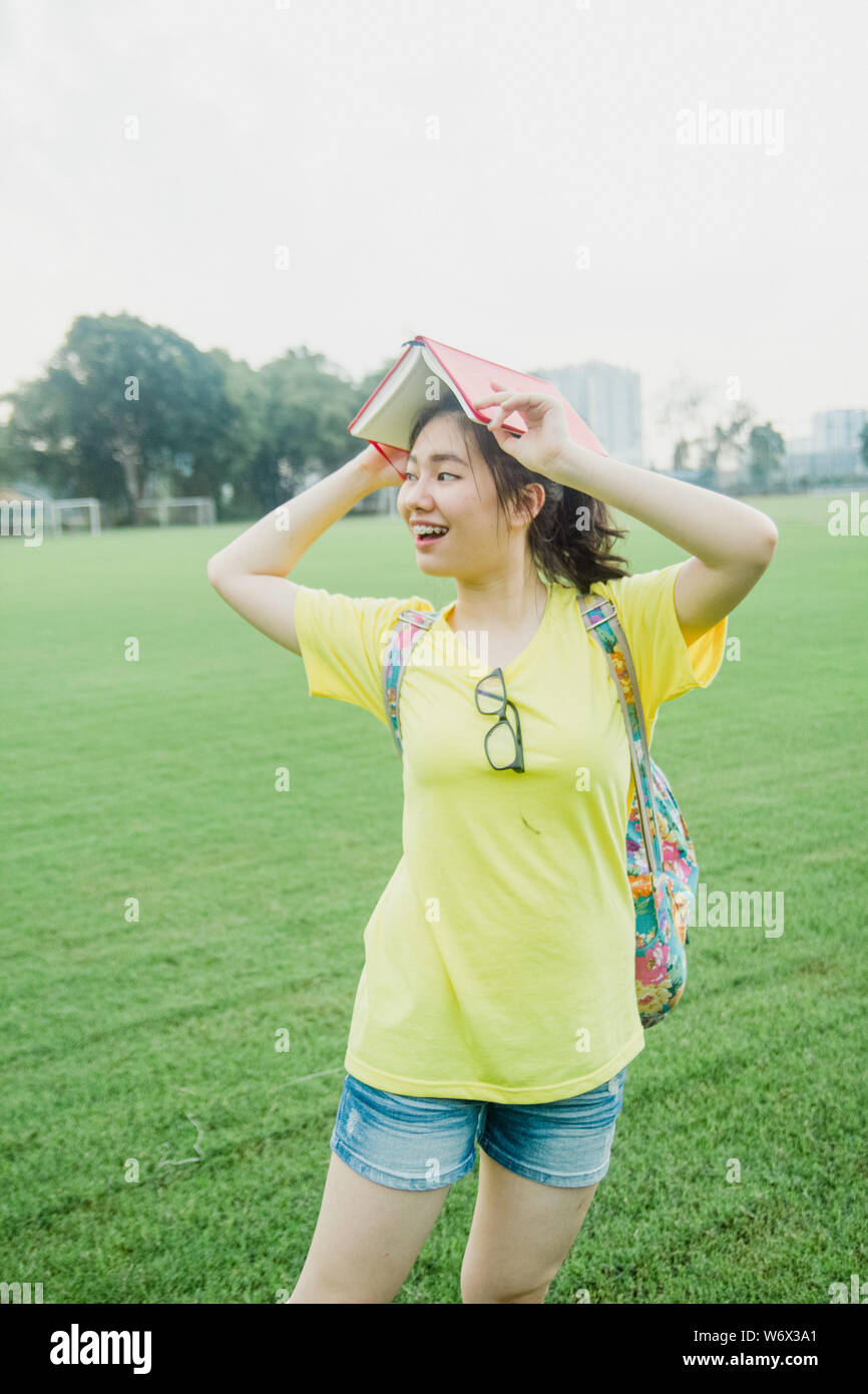 Young girl student having fun on grass field in the afternoon in campus ...