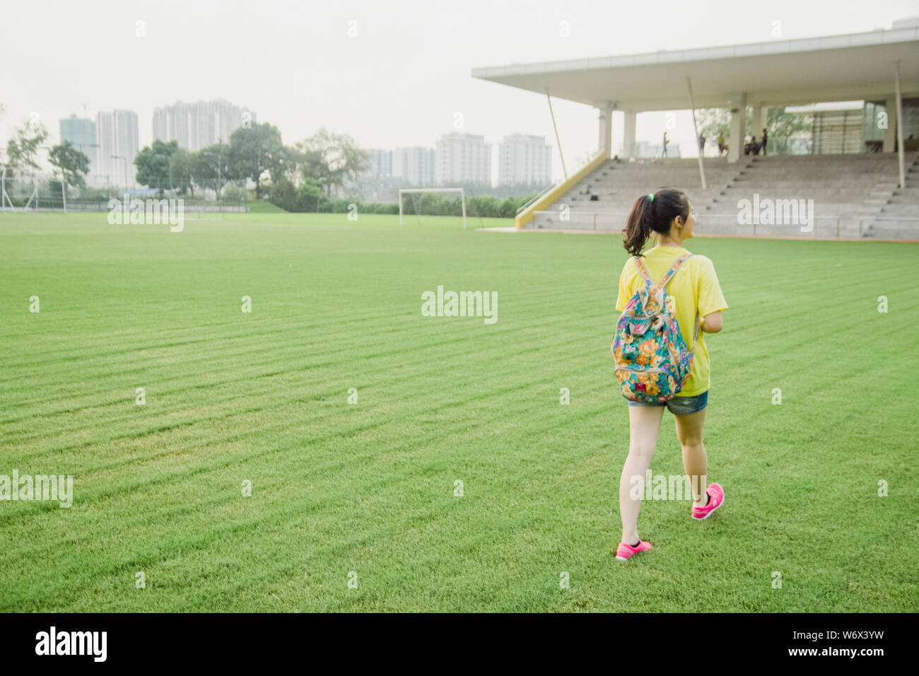 Young girl student having fun on grass field in the afternoon in campus ...