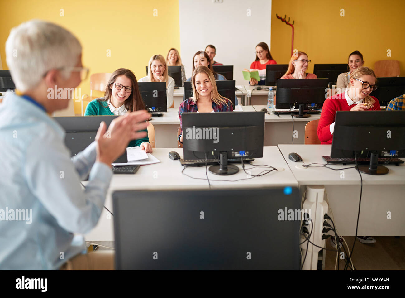Smiling University students sitting together at table using computer in ...