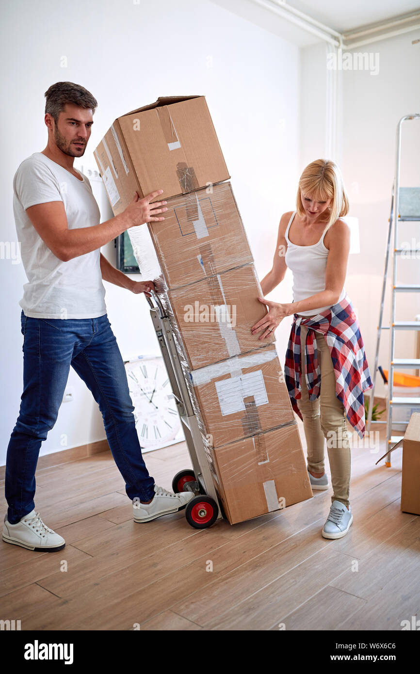 couple moving in new home. Happy man and woman with cardboard boxes ...