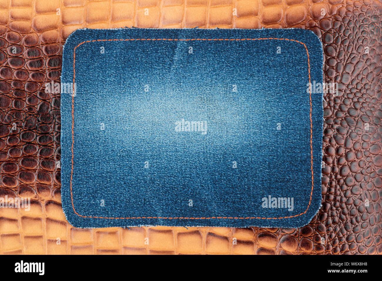 Blank jeans frame. Denim patch with orange thread seam on brown skin ...