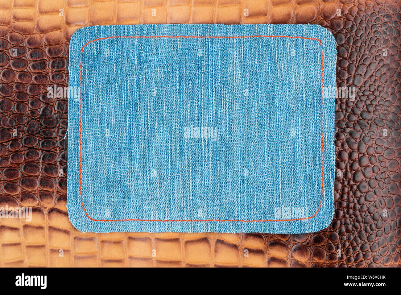 Blank jeans frame. Denim patch with orange thread seam on brown skin ...