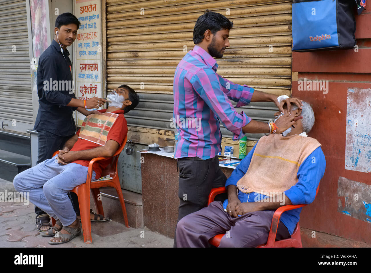 Two customers being shaved at an open-air barber 'shop' in Kalbadevi ...