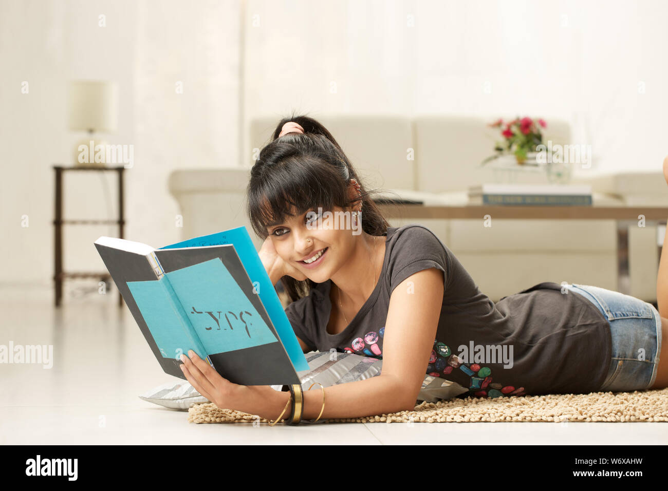 Woman lying on floor and reading a book Stock Photo - Alamy