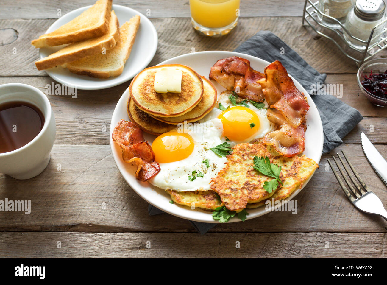 Full American Breakfast on wooden, close up. Sunny side fried eggs, roasted bacon, hash brown ...