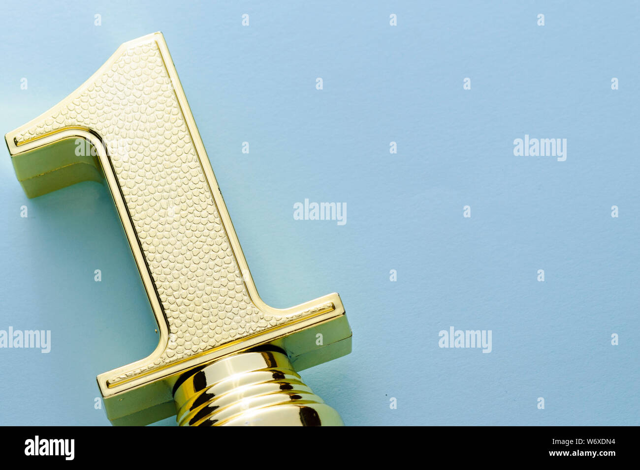 Textured decorative gold winners trophy number one over a grey stdio ...