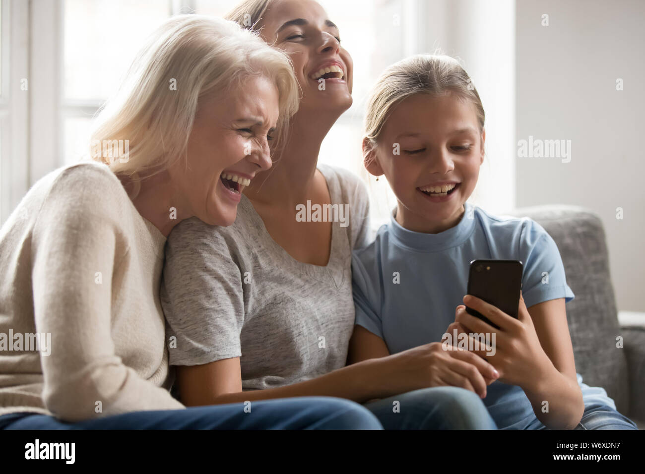 Laughing three generations of women having fun using smartphone Stock ...