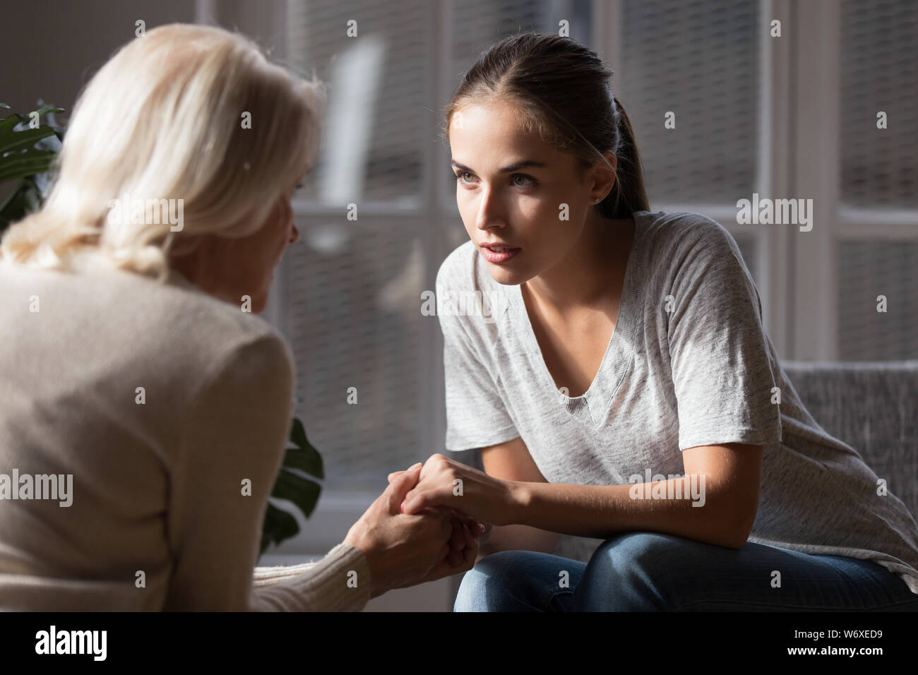 Daughter holding hands aged mother having heart-to-heart talk Stock ...