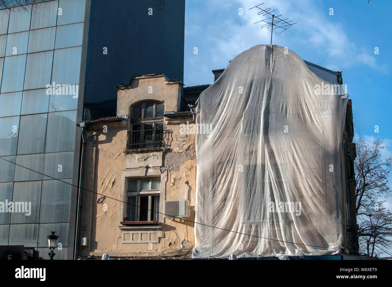 Side by side contemporary building, old neglected house and house under ...
