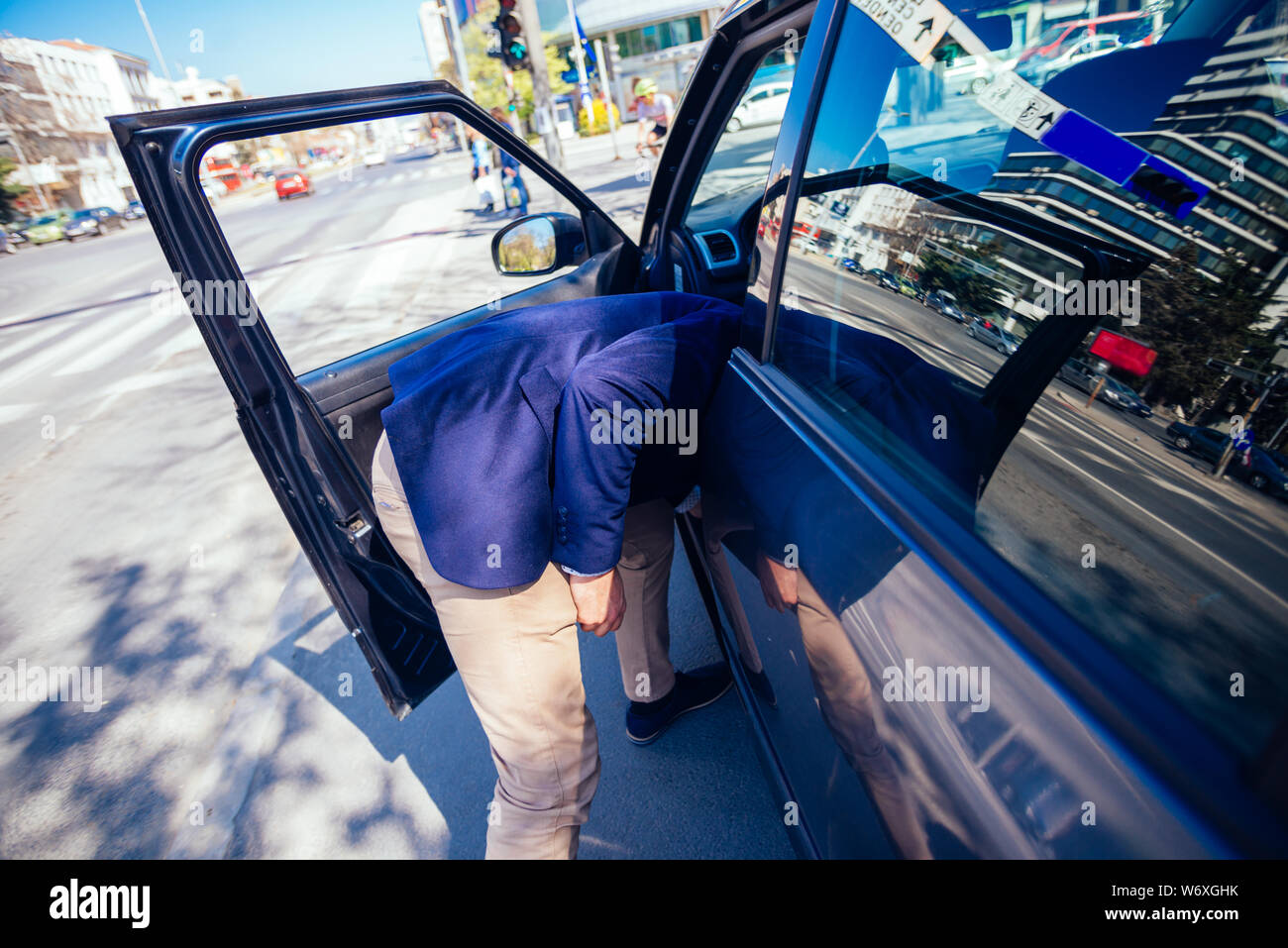 Happy entrepreneur opening his car door and inspecting the interior of ...