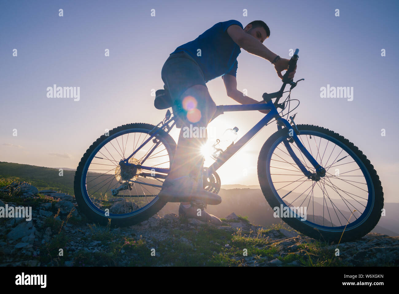 Strong fit male mountain biker performing stunts on rocky terrain on a ...
