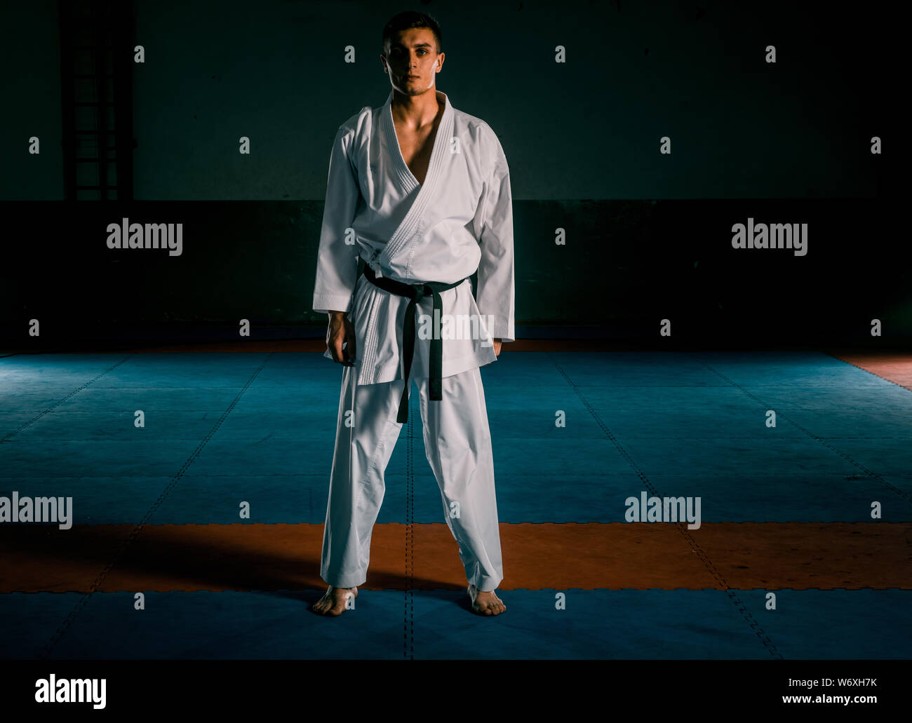 Strong fit athlete, karate man or fighter in white kimono, suit, with ...