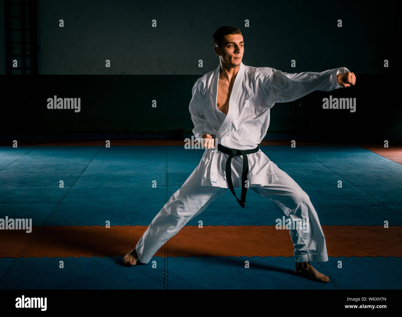 Strong fit athlete, karate man or fighter in white kimono, suit, with ...