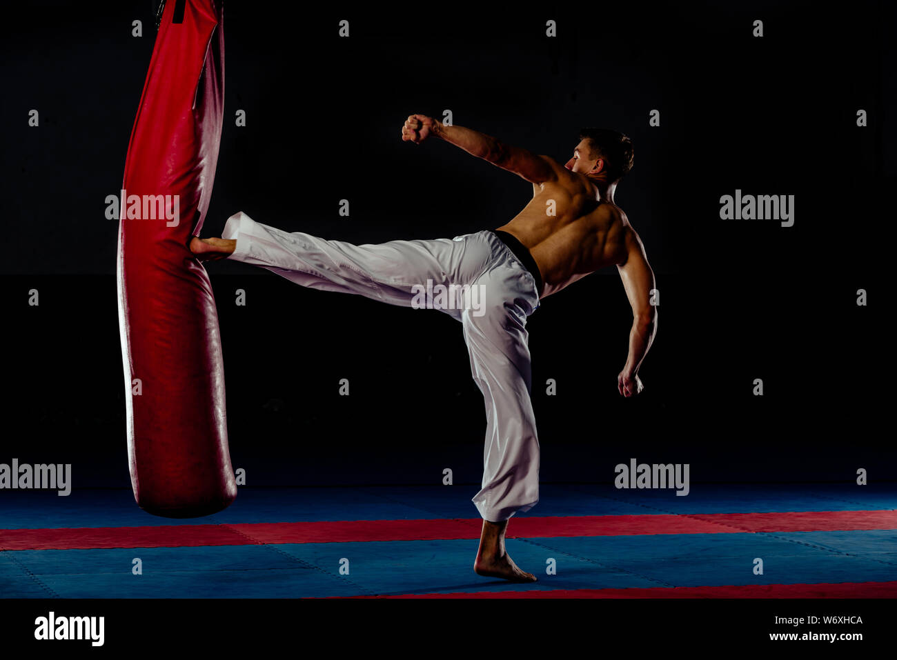 Muscular handsome fighter giving a forceful forward kick during a ...