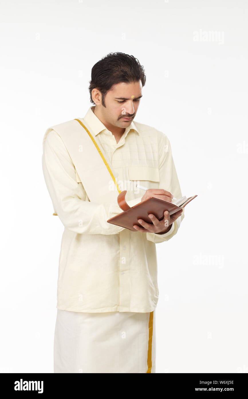 South Indian man writing on a personal organizer Stock Photo - Alamy