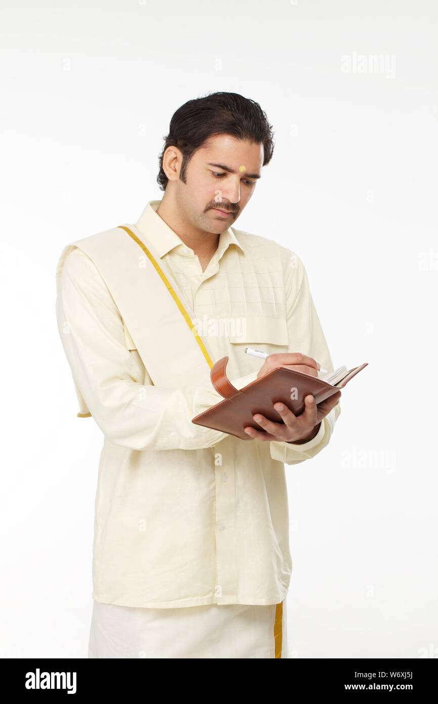 South Indian man writing on a personal organizer Stock Photo - Alamy