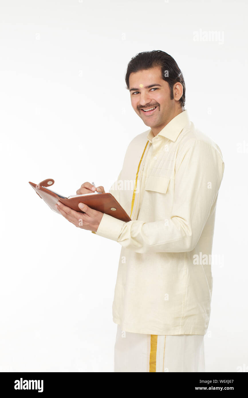 South Indian man writing on a personal organizer Stock Photo - Alamy