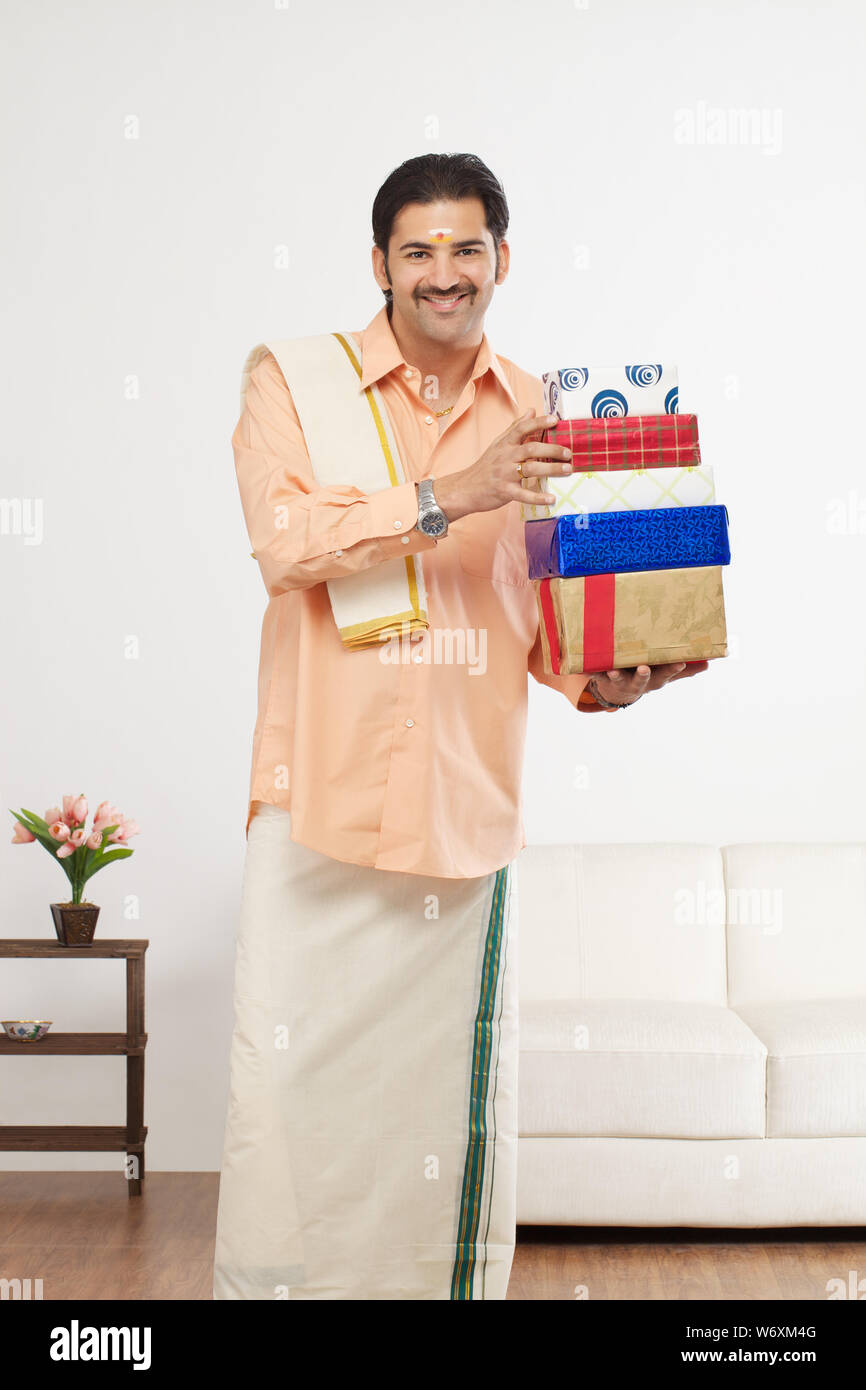 South Indian man holding gift boxes and smiling Stock Photo - Alamy