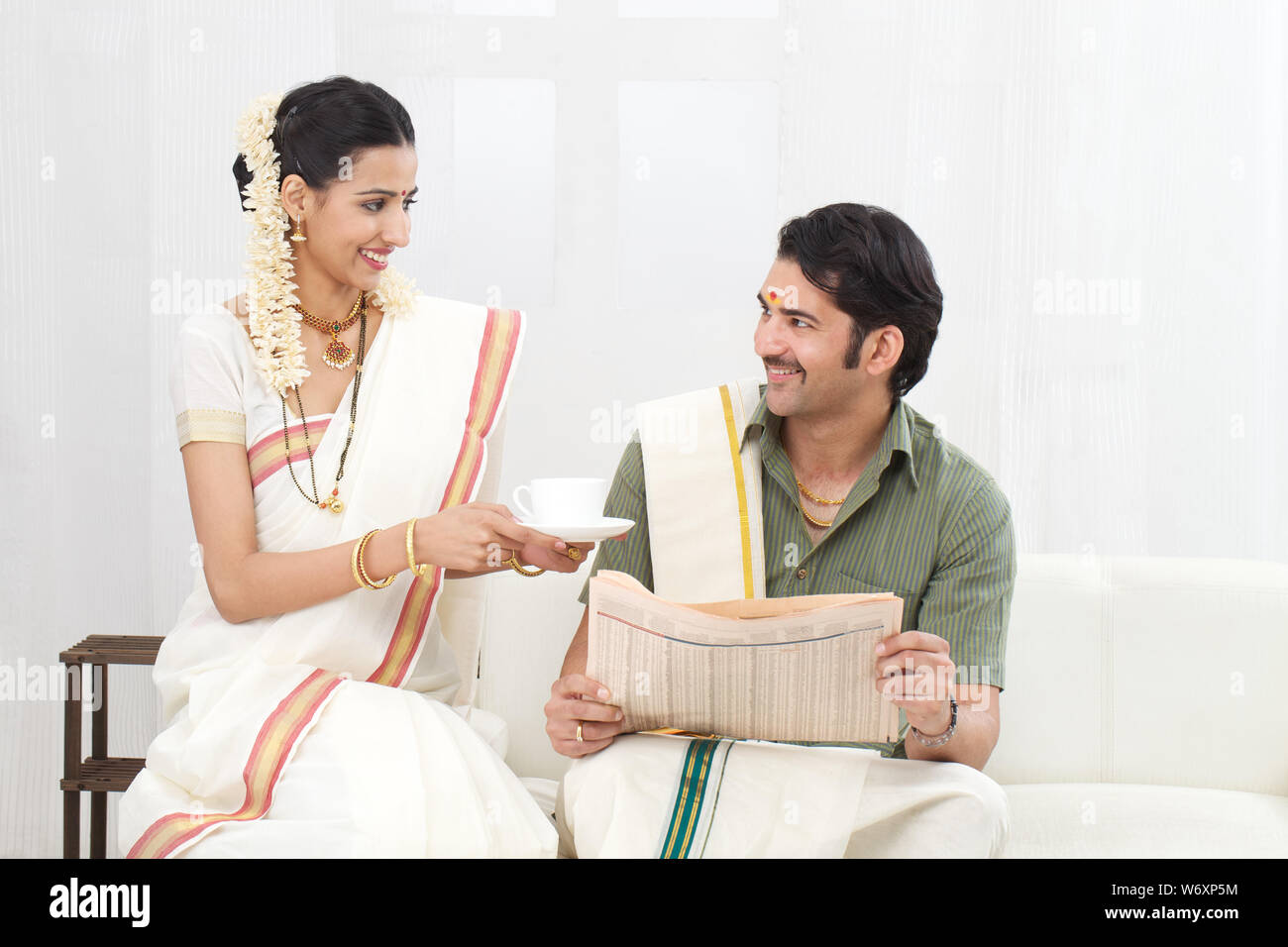South Indian woman giving a cup of tea to her husband Stock Photo - Alamy