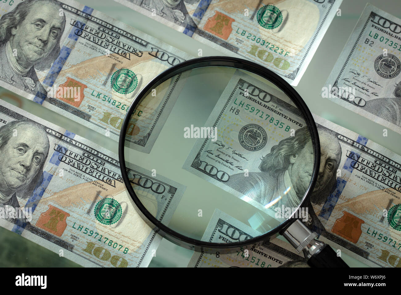 American money hundred dollar bills and magnifier on a glass background ...